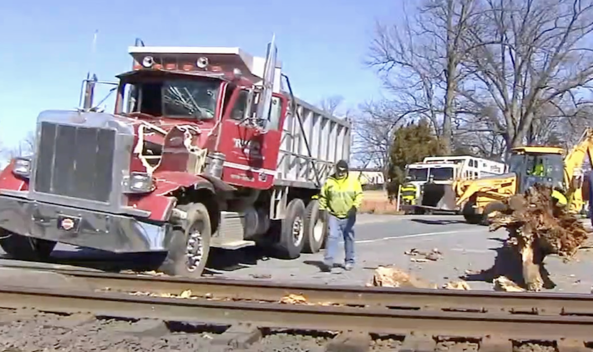 Fallen tree pins dump truck dangerously close to train tracks